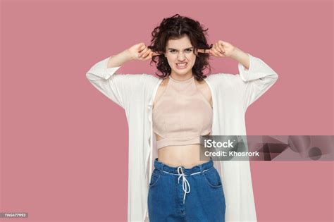 나는 이것을 듣고 싶지 않아요 불만족 한 갈색 머리의 초상화 캐주얼 스타일의 곱슬 헤어스타일을 가진 젊은 여자는 서 있고 그녀의 귀에 손가락을 넣어 가리기에 대한 스톡 사진