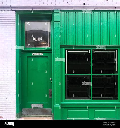 A Vibrant Green Storefront With Vintage Signage Against A White Tile