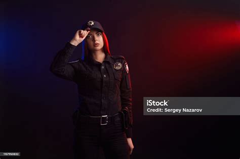심각한 여성 경찰관은 빨간색과 파란색 백라이트와 검은 배경에 대한 카메라를 위해 포즈를 취하고있다 경찰관에 대한 스톡 사진 및 기타 이미지 Istock