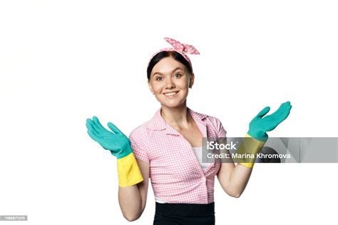 활짝 웃는 청소를위한 고무 장갑이있는 분홍색 셔츠를 입은 아름다운 핀 업 소녀는 팔을 좌우로 펼치고 손바닥을 위로 벌리고 흰색 배경에 고립되었습니다 가사 집안일에 대한 스톡