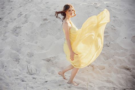 아름 다운 Boho 소녀 호수 근처 일몰 빛 모래 해변에 산책 휴식 재미와 실행 바람 머리와 노란색 드레스를 입고 매력적인 젊은 여자 여름 휴가 개념에 대한 스톡 사진 및