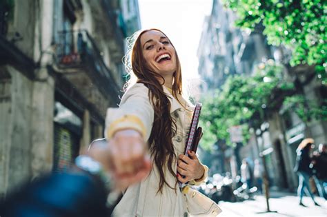 여름 방학이나 신혼 여행 중 도시의 도시 환경에서 기뻐하는 쾌활한 힙스터 소녀의 초상화 빨간 머리카락을 가진 행복한 백인 여성 관광객이 손을 잡고 카메라를 비웃는 모습 25