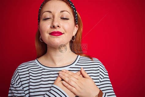 美丽的红发女人穿着条纹海军t恤站在孤立的红色背景上高清图片下载 正版图片504206208 摄图网