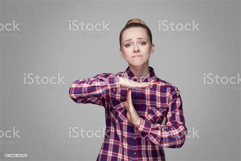 분홍색 체크 무늬 셔츠에 아름 다운 금발 여자 수집 롤빵 헤어스타일 서 타임 아웃 제스처와 함께 카메라를 바라보 고 더 많은 시간에 대 한 구걸 경계 표지에 대한 스톡 사진