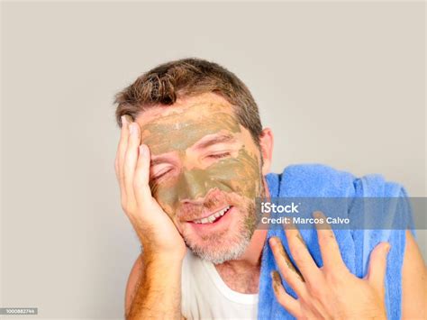 라이프 스타일 욕실 수건 녹색 크림 피부 관리 뷰티 얼굴 마스크를 적용 하는 그의 얼굴에 미소와 매력적이 고 행복 한 젊은이의 초상화를 격리 하 고 개념을 사용 하는 남성