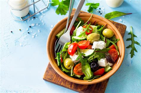 สลัดกรีกกับผักสดชีส Feta และมะกอกดําบนหินสีฟ้าหรือโต๊ะคอนกรีต อาหาร