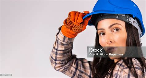 파란 헬멧과 장갑을 낀 젊은 미숙련 여성의 초상화가 카메라를 바라보며 옆공간을 가진 흰색 배경을 배경으로 포즈를 취하고 있다 건강관리와 의술에 대한 스톡 사진 및 기타