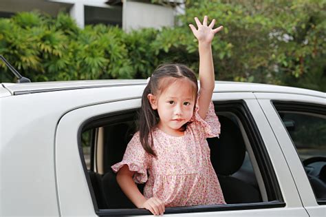 자동차 웃 고 작별 인사를 흔들며 차 뒷좌석에 앉아 카메라를 보고 있는 귀여운 아시아 작은 소녀 굿바이 낱말에 대한 스톡 사진 및 기타 이미지 Istock