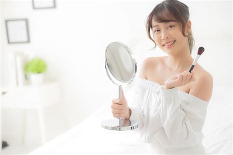 뷰티 초상화 젊은 아시아 여성은 침실에 브러시 뺨과 메이크업을 적용 얼굴을 찾고 거울 블러셔를 들고 여자의 아름다운 스킨 케어 및 화장품 개념으로 미소 가정 생활에 대한