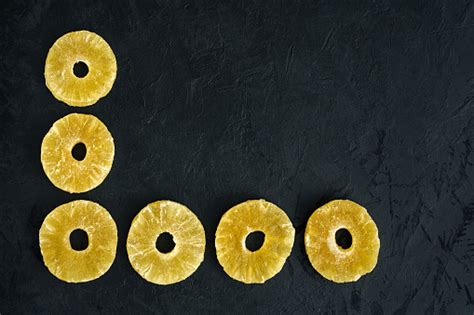 설탕에 절인 말린 파인애플의 여섯 반지는 검은 색 콘크리트 배경에 가장자리 프레임의 형태로 조각 평면도 0명에 대한 스톡 사진 및 기타 이미지 Istock