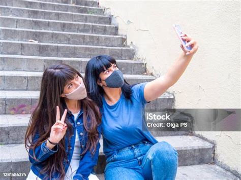 밖에서 핸드폰을 들고 얼굴 마스크를 쓰고 셀카를 찍고 있는 두 명의 청녀 25 29세에 대한 스톡 사진 및 기타 이미지 25 29세 2명 30 34세 Istock