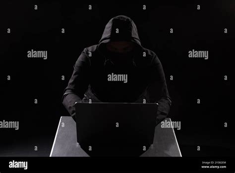 cyber hacker in hood behind laptop in dark room digital cyber security