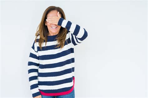 아름 다운 중 년 여자는 웃 고 놀람에 대 한 눈을 덮고 얼굴에 손으로 고립 된 배경 위에 해군 스웨터를 입고 눈 먼 개념입니다