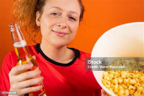 빨간 티셔츠를 입고 맥주 한 병과 팝콘 한 그릇을 들고 포즈를 취한 빨간 머리 의 여성 팬의 자른 사진 격려에 대한 스톡 사진 및 기타 이미지 Istock