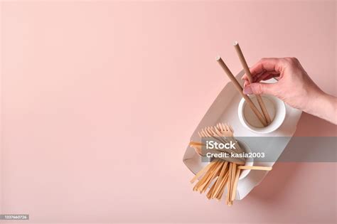 여성의 손은 칵테일 빨대 종이 컵 요리 나무 포크 마시는 빨대 패스트 푸드 용기 분홍색 배경에 나무 칼을 합니다 에코 크래프트