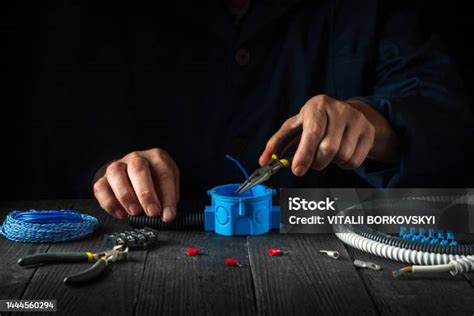작업 중 마스터 전기 기술자의 손을 클로즈업합니다 파란색 정션 박스에 케이블 또는 와이어 설치 전기 장비의 설치 및 수리에 대한 아이디어 개체 그룹에 대한 스톡 사진 및