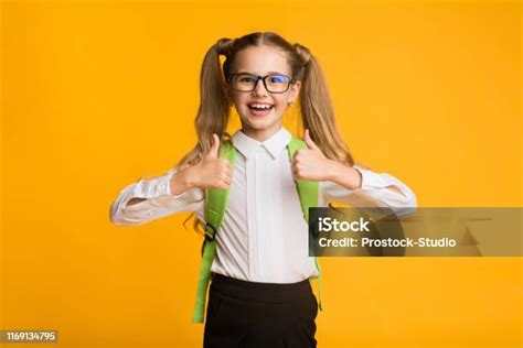 쾌활한 어린 여학생 몸짓 엄지 손가락 업 와 양손 노란색 배경 개념에 대한 스톡 사진 및 기타 이미지 개념 고등학교 이하 공부 Istock