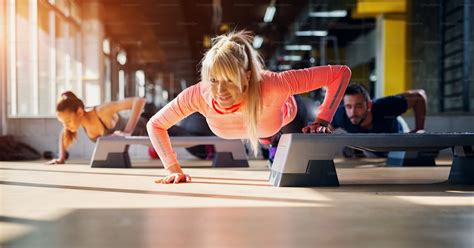 세 명의 강한 젊은 운동 선수가 스테퍼에 한 손으로 팔 굽혀 펴기를하고 있습니다 사진 Unsplash의 마루 이미지