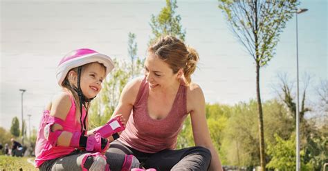 스케이트를 탄 후 어린 딸이 도로에 앉아 웃고 있는 어머니 사진 Unsplash의 딸 이미지