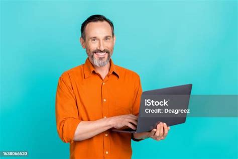 흰 회색 턱수염을 가진 쾌활하고 영리한 좋은 남자의 사진은 청록색 배경에 격리된 Lapotop에 이메일을 입력하는 세련된 셔츠를