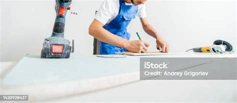 특수 유니폼을 입은 건설 노동자와 공구 중 귀 보호기가 개조 공사를 진행합니다 석고보드에 대한 스톡 사진 및 기타 이미지 석고보드 드릴 비즈니스 Istock