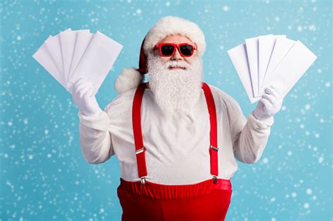 특별 배송 연금 수령자 노인 회색 수염 보류 부채 봉투 급사 우편물을 가져다 동료들이 입고 있다 산타 복장 멜빵 선글라스 흰 장갑 모자 외딴 파란색 배경 봉투에 대한 스톡