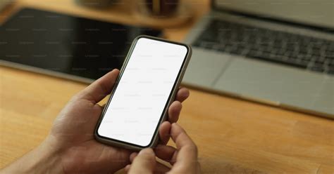 노트북과 태블릿이 있는 나무 테이블에 스마트폰을 들고 있는 손의 보기를 닫습니다 사진 Unsplash의 태국 이미지