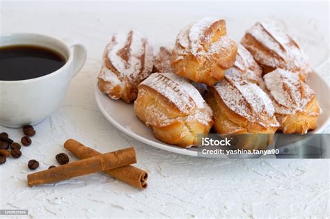 흰색 테이블에 접시에 집에서 만든 바닐라 에클레어 또는 이익 복사 공간을 복사합니다 커피 콩과 아니스 스타 흰색 테이블에 계피 스틱 전통적인 프랑스 맛있는 디저트와 커피 컵