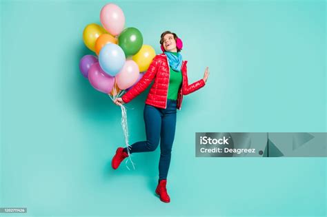 재미 차가운 아가씨의 전신 사진 생일 파티 는 캐주얼 빨간 코트 스카프 핑크 귀 머프 바지 신발 고립 된 청록색 색상 배경을 착용 하는 많은 화려한 공기 풍선을 가지고