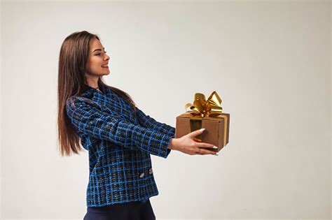 회색 스튜디오 배경에서 선물 상자를 들고 있는 즐거워하는 완벽한 여자 모델 행복 한 곳을 바라보고 있습니다 현재의 감정을 보여주는 블루 재킷을 입은 세련된 슬림 아가씨 패션