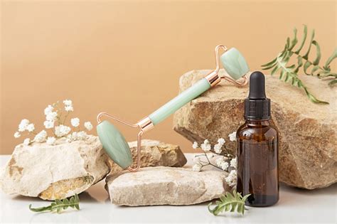 녹색 옥 롤러 얼굴 마사지 기 Gouache 밝은 갈색 베이지 색 배경에 돌에 녹색 잎과 석고 필라의 흰색 꽃 홈 스파 케어 아름다움과 젊음 안티 에이지의 개념 0명에 대한