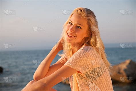 日落时分美丽的金发女郎在海滩上休息