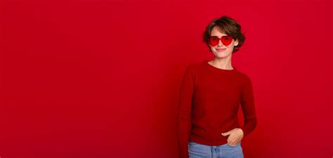 빨간 밝은 벽에 고립 된 하트 모양의 안경을 쓴 귀엽고 자신감 있는 트렌디 한 착용 여성의 배너 이미지 좋은 기분과 사랑의 감정을 가진 소녀 25 29세에 대한 스톡 사진