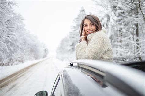 아름다운 젊은 여성이 눈 덮인 숲을 통과하는 길에 쉬고 차의 선루프를 통해 서있는 아름다운 자연을 관찰합니다 겨울 방학 30 34세에 대한 스톡 사진 및 기타 이미지