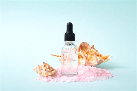 드롭퍼 투명 유리 화장품 병 모의 분홍색 바다 소금과 파란색 배경에 조개 친환경 케어 유기농 제품 뷰티 트리트먼트 스파 컨셉