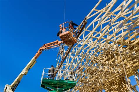 Construction Workers Assembling Wooden Structure On Clear Day In