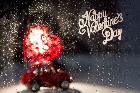 비오는 창문 뒤 지붕에 하트가 있는 빨간 복고풍 장난감 자동차 발렌타인 데이에 카페와 레스토랑에서 음식 배달코로나 바이러스로 인한 도시의 차단 제한 및 슬픔 0명에 대한