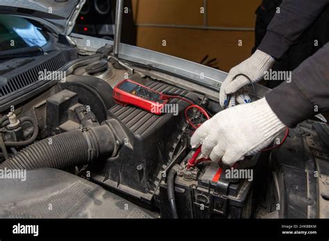 Selective Focus An Auto Mechanic Uses A Multimeter Voltmeter To Check The Voltage Level In A Car