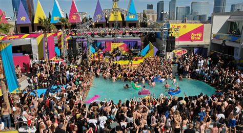 A Large Group Of People Standing Around In Front Of A Pool