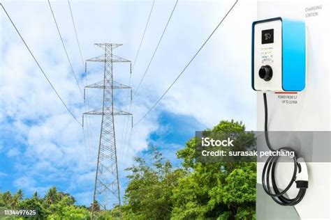 녹색 나무 배경으로 자연적인 파란 하늘과 고전압 전기 폴란드에 전기 차 충전 또는 잡종 차를 위한 현대 Ev 역 플러그 및 전원 케이블 공급 연료 및 전력 생산에 대한 스톡