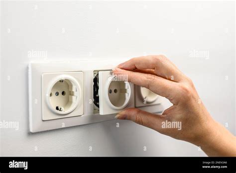Installing A White AC Wall Socket With A Screwdriver On A White Wall Home Renovation Stock