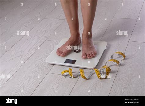 Eating Disorder Woman Standing On Floor Scale And Measuring Tape