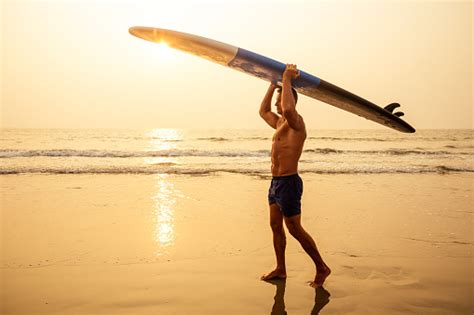 잘 생긴 핏 맨은 검은 흰색 파란색 서핑 보드로 바다 해변 근육에서 서핑 스팟에서 파도를 기다리고 스포츠 훈련 체육관 남성 피트니스 모델을 누릅니다 널판지에 대한 스톡 사진