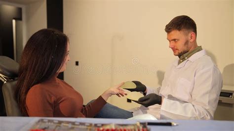 The Doctor Holds Two Silicone Implants In His Hands The Patient Tries