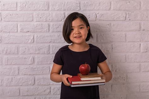 학교로 돌아갑니다 어린 소녀는 하얀 벽돌 벽 근처에 책과 사과를 들고 있다 초등학교 부터 아이 1위에 대한 스톡 사진 및 기타 이미지 Istock
