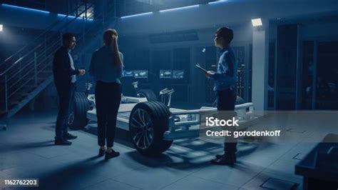 타이어 서스펜션 엔진 및 배터리를 포함하는 전기 자동차 플랫폼 섀시 프로토 타입에서 작업 하는 자동차 혁신 시설에서 자동차 디자인 엔지니어의 팀 3차원 형태에 대한 스톡