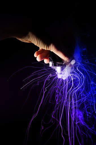 남성 손은 Vape 거꾸로 유지 Vape 구름 검은 배경에 코일에서 시작 합니다 안개는 두 가지 색상의 파란색과 보라색입니다 재고 격리 이중 색상 연기 스프레이 끓는 글