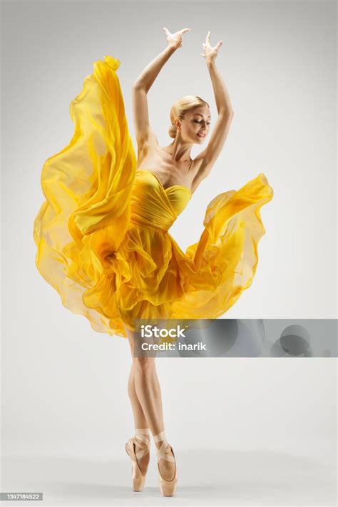 노란색 드레스를 입은 춤추는 여자 신발의 발레리나는 밝은 회색 배경을 통해 현대 미술 발레 를 춤 우아한 소녀 스트레칭 손 발레