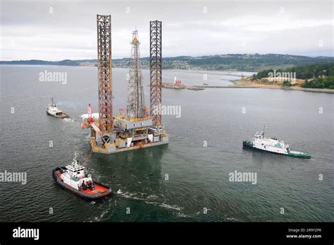 Aerial Image Of An Oil Drilling Rig Being Towed Out Of Port By Three