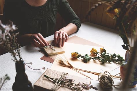 여자는 제로 폐기물 플라스틱 무료 트렌디 한 손으로 만든 선물 패키지를 공예 재활용 종이와 린넨 식탁보와 테이블에 말린 꽃 천연 에스테틱 가을에 대한 스톡 사진 및 기타